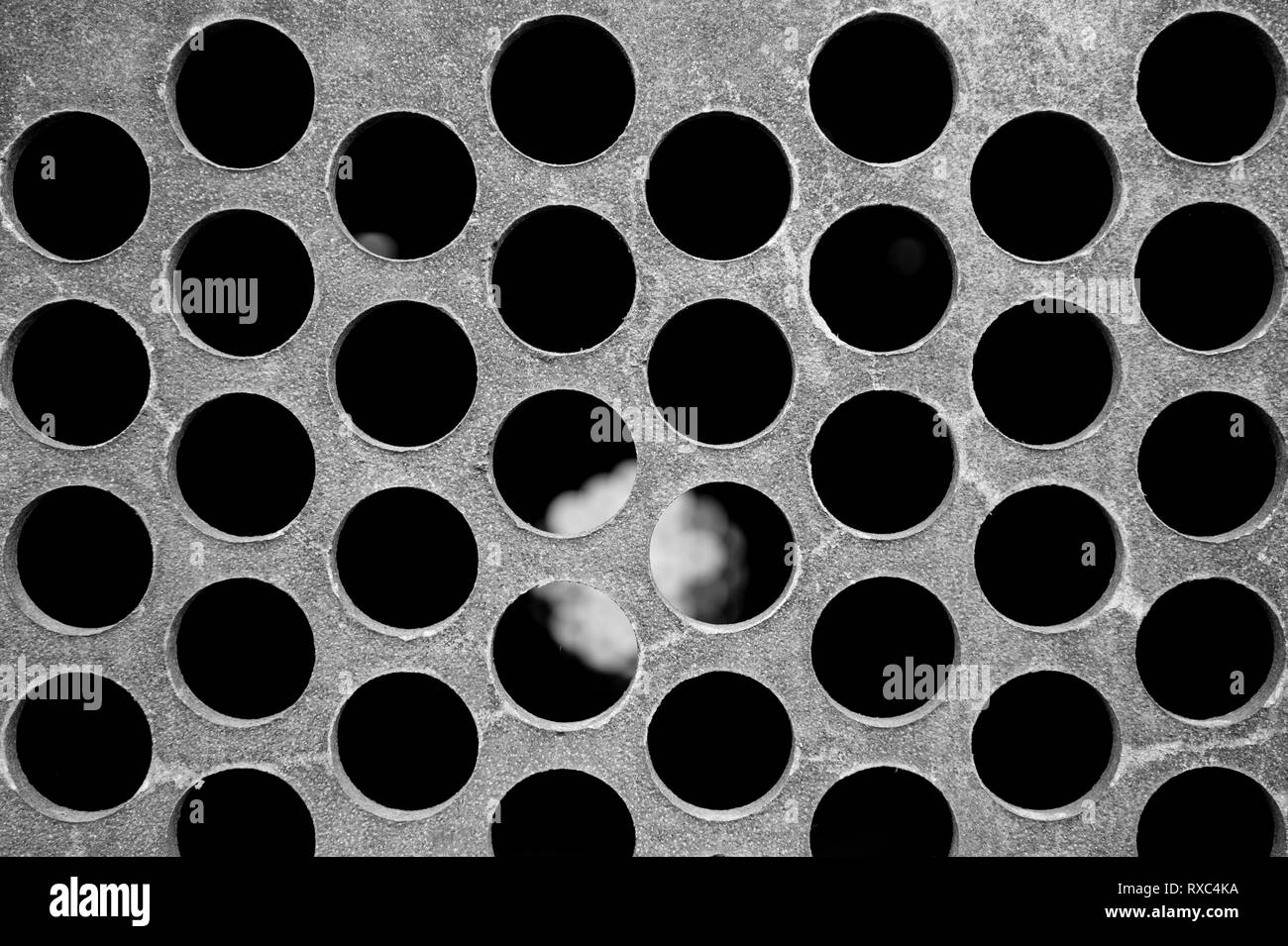 Pattern of round holes in a thick metal plate, part of a steam engine ...