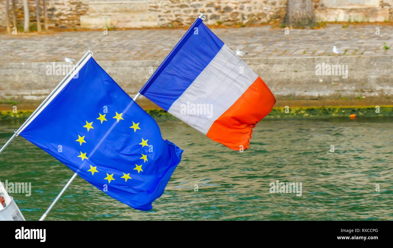 Two flags are on the edge of the boat. The boat cruising on the Siene ...