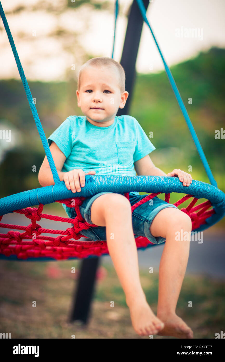 Little boy swinging on a swing at kids playground outdoor Stock Photo ...