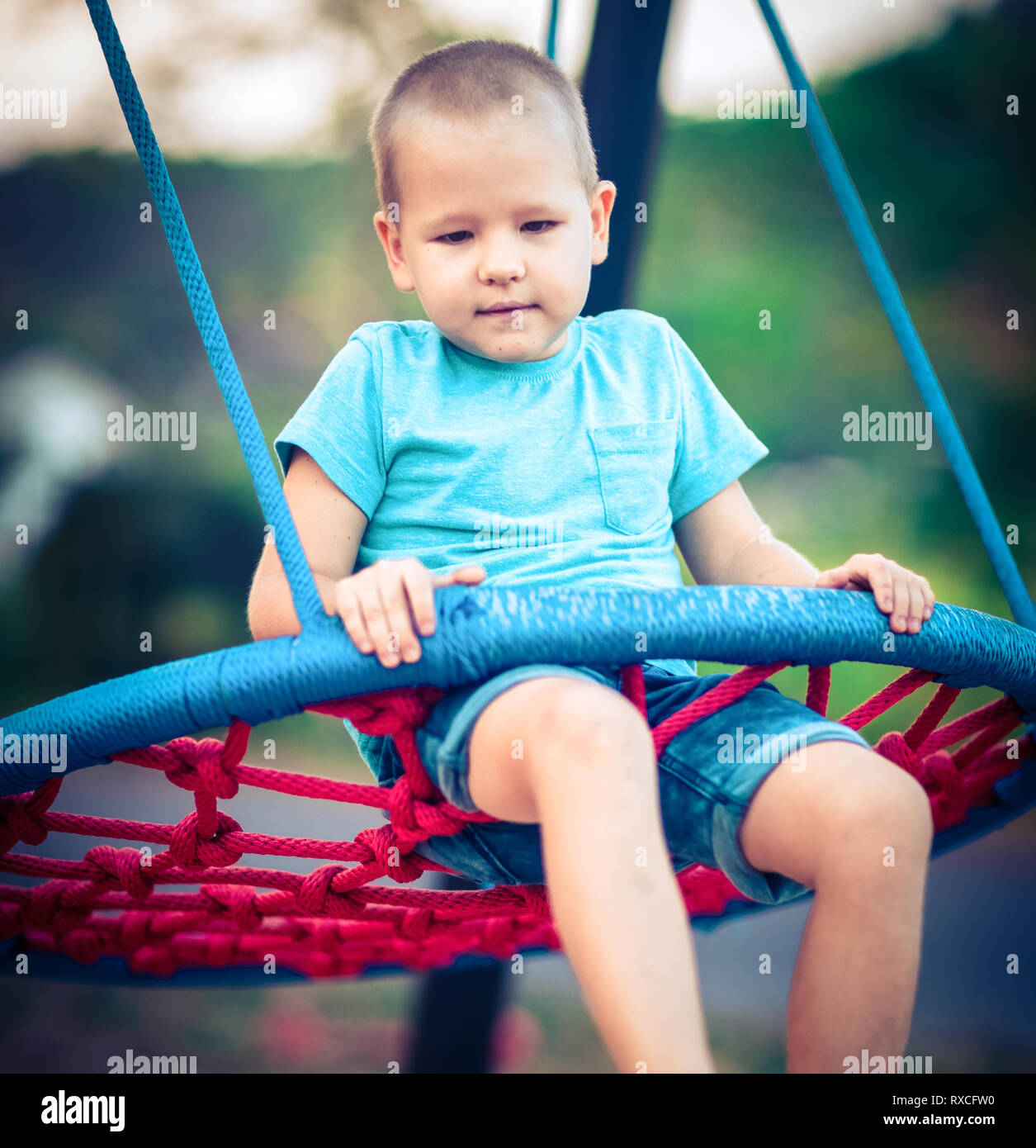 Little boy swinging on a swing at kids playground outdoor Stock Photo ...