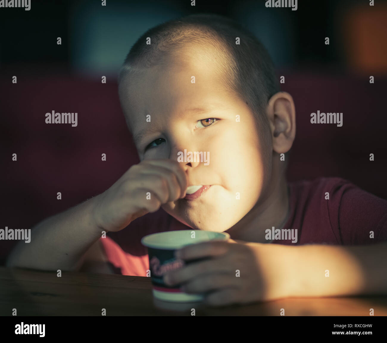 Portrait of a boy eating ice cream. High contrast hard light portrait ...