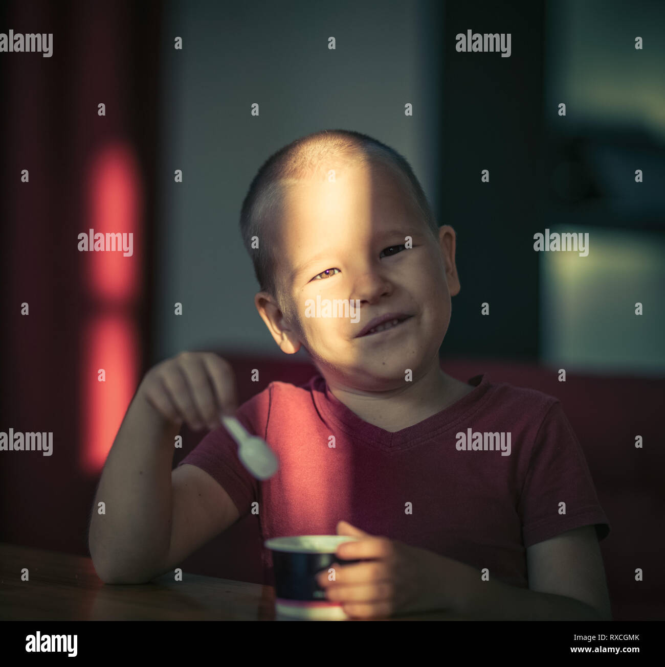 Portrait of a smiling boy eating ice cream. High contrast hard light ...