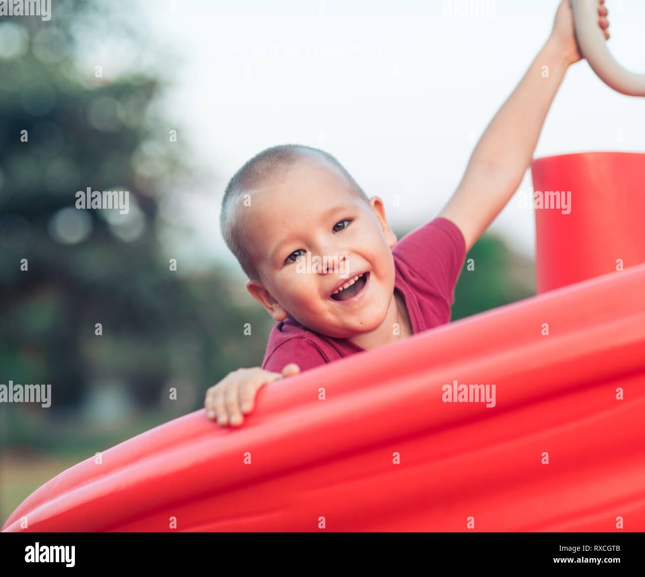 Little smiling boy playing on a slide. Outdoor activity Stock Photo - Alamy