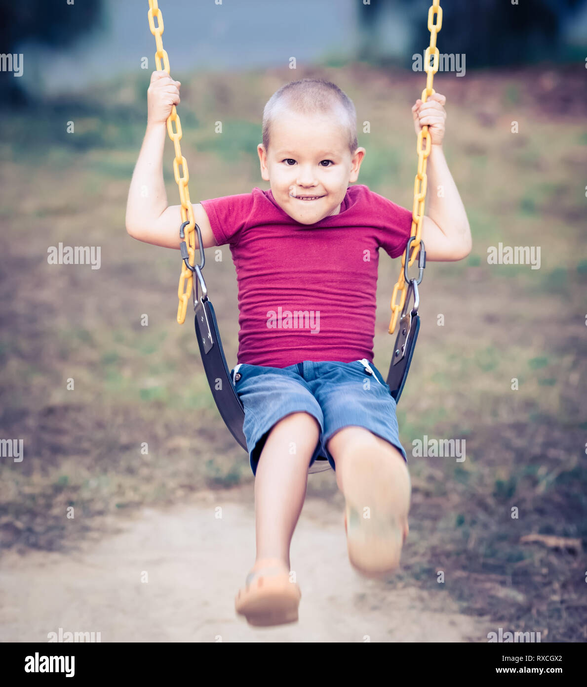 Little boy swinging on a swing at kids playground outdoor Stock Photo ...