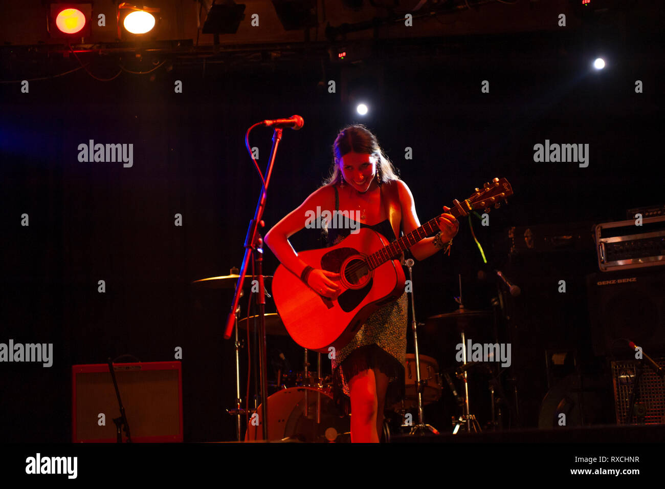 Female singer with acoustic guitar playing on stage Stock Photo - Alamy