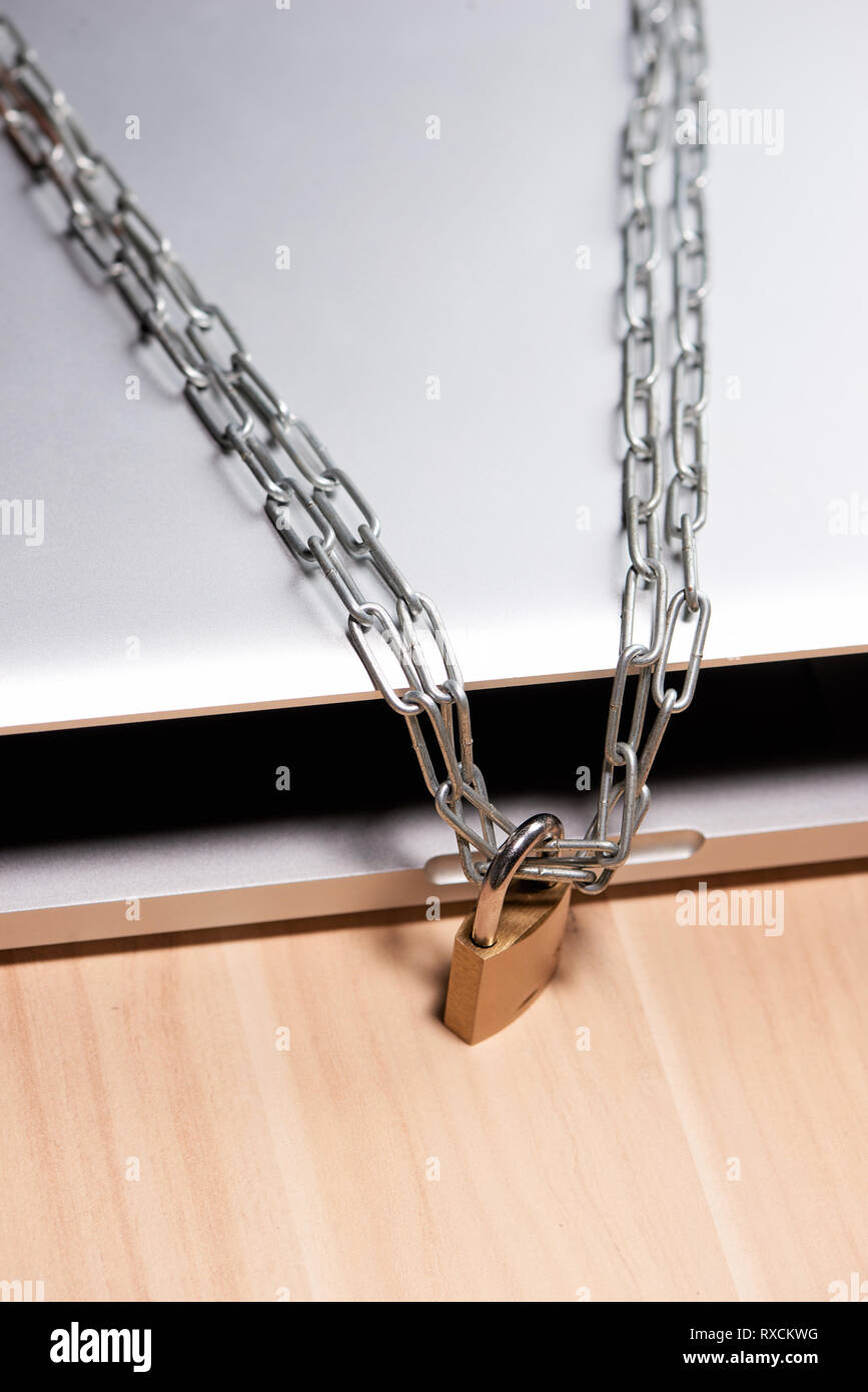 Heavy chain with a padlock around a laptop on table Stock Photo - Alamy