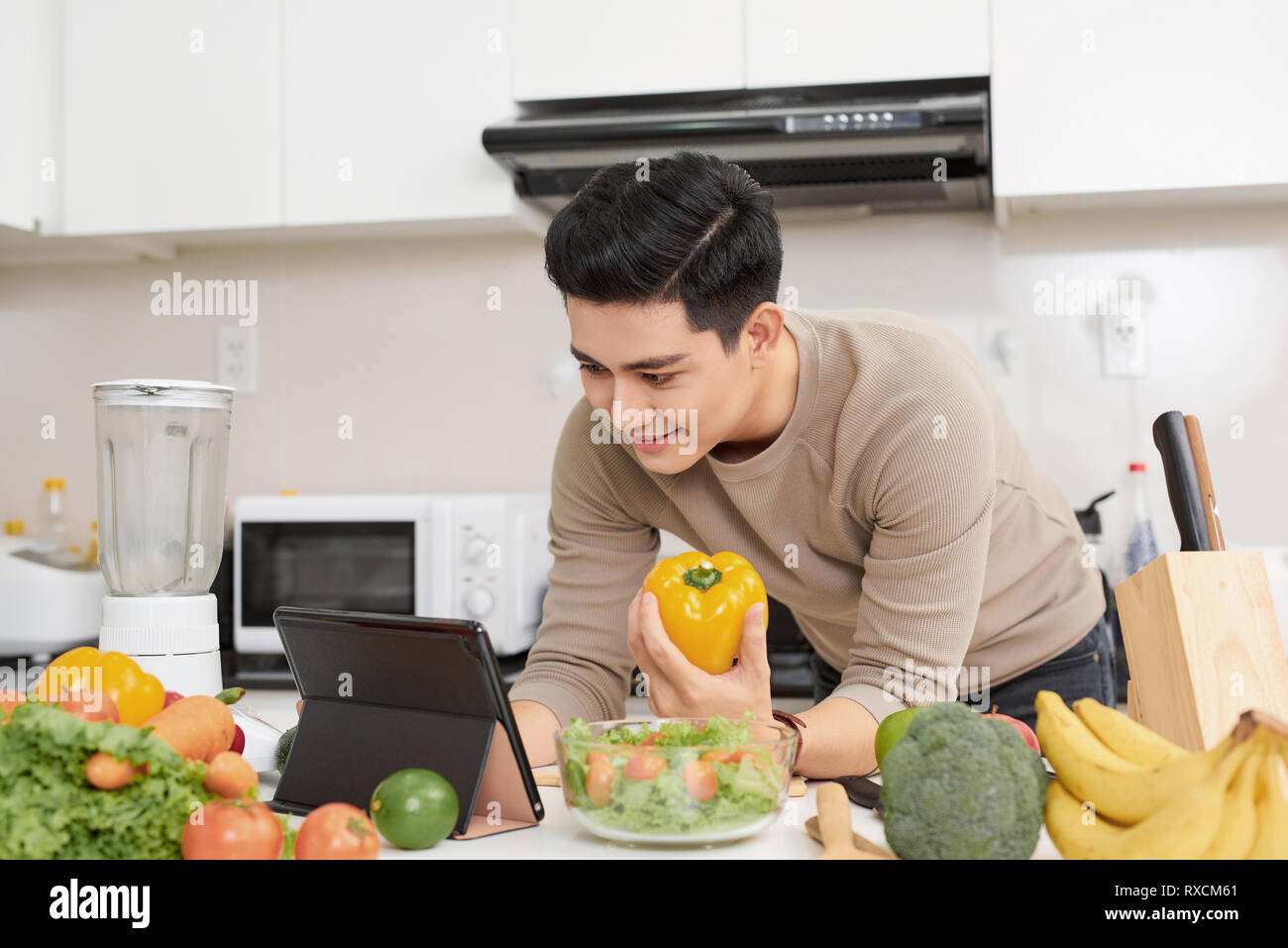 Man cooking at home in kitchen, using tablet computer Stock Photo - Alamy