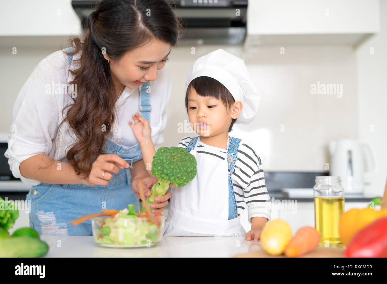 Mother with her daughter preparing lunch in the kitchen and enjoying ...