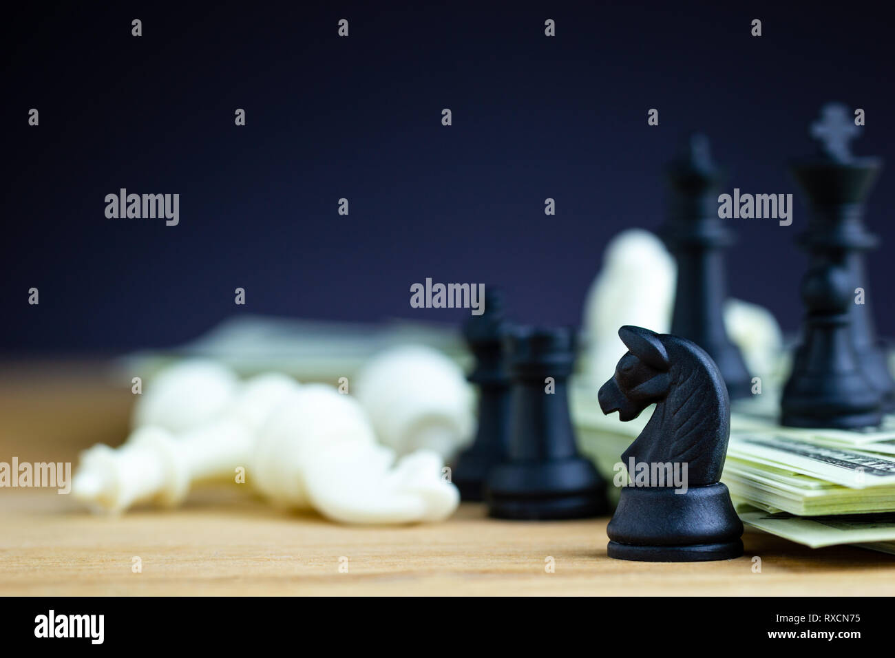 Black chess stands on top of dollar banknotes and wooden tables with ...