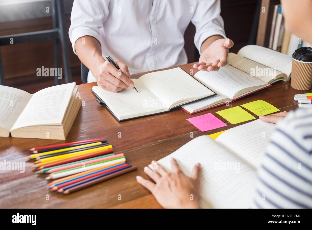 Young students classmates help friend catching up workbook and learning ...