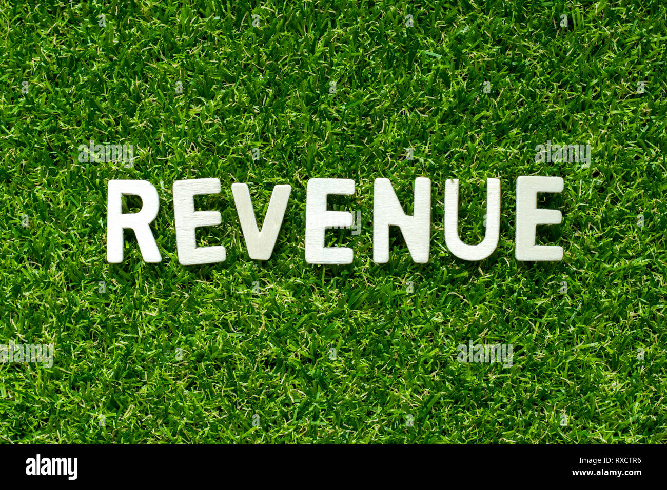 Wood alphabet in word revenue on artificial green grass background ...
