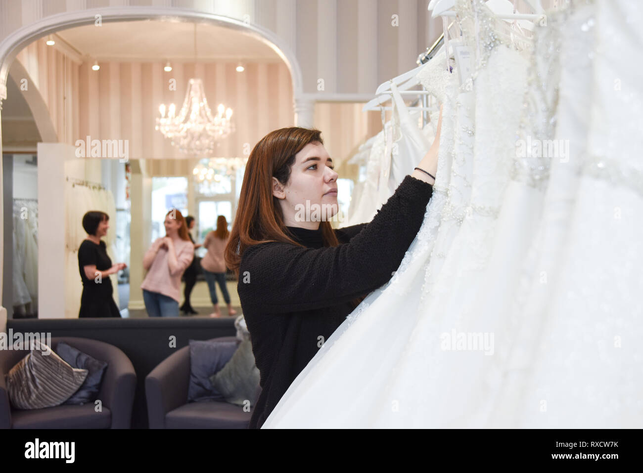 2 shop assistants are helping a pretty red haired girl in a Wedding ...