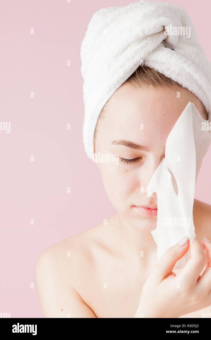 Beautiful young woman is applying a cosmetic tissue mask on a face on a ...