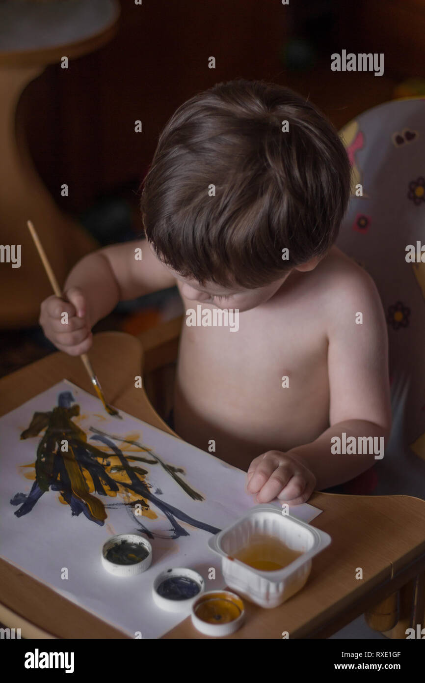 boy paints on paper. children's activities. Hobby - drawing. little boy ...