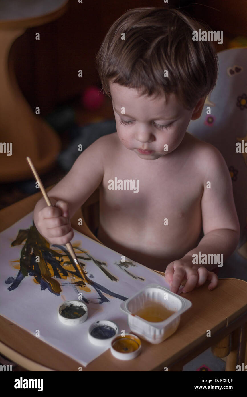 boy paints on paper. children's activities. Hobby - drawing. little boy ...