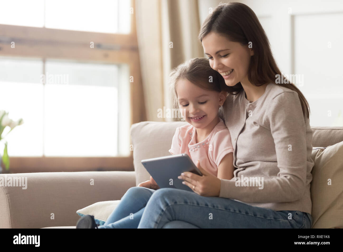 Happy mom and kid daughter using digital tablet on sofa Stock Photo - Alamy