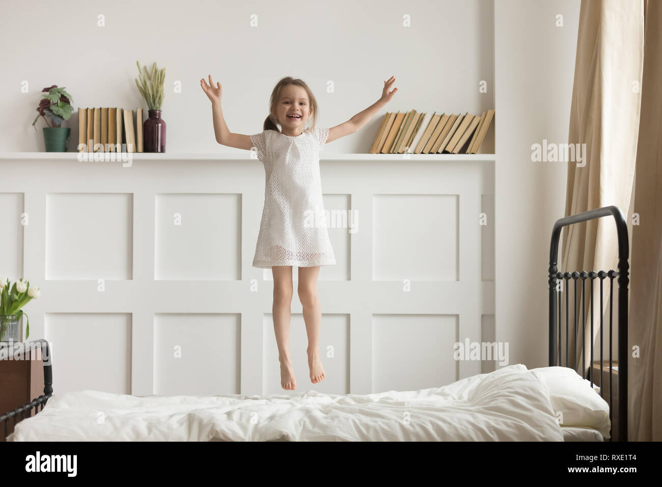 Happy funny child girl jumping on bed alone feeling joy Stock Photo - Alamy