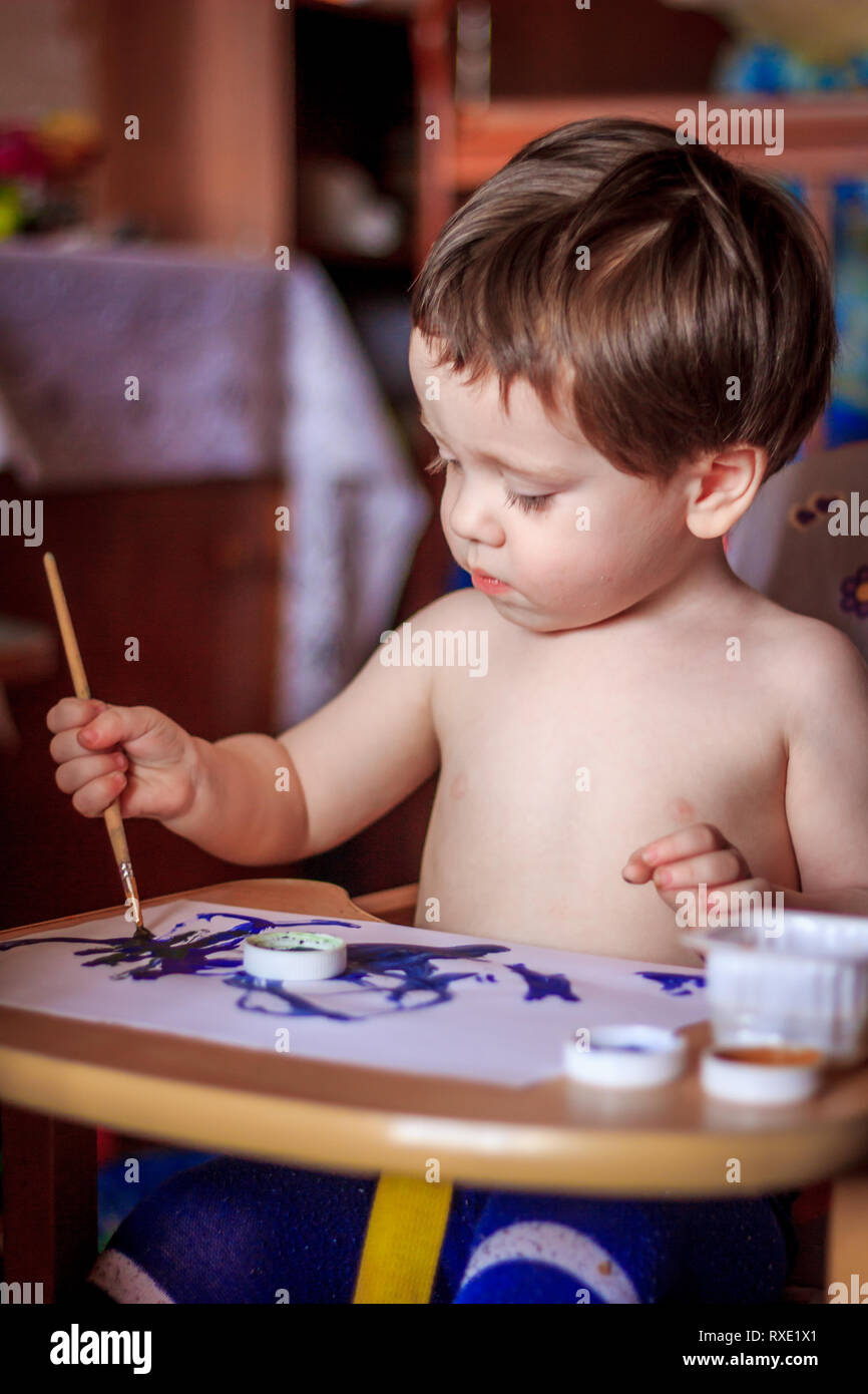 boy paints on paper. children's activities. Hobby - drawing. little boy ...