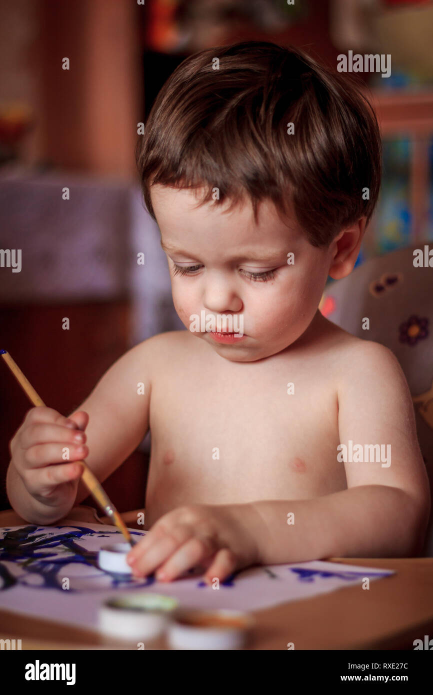 boy paints on paper. children's activities. Hobby - drawing. little boy ...