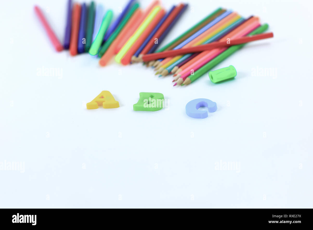 colored pencils and letters of the alphabet on a white background ...