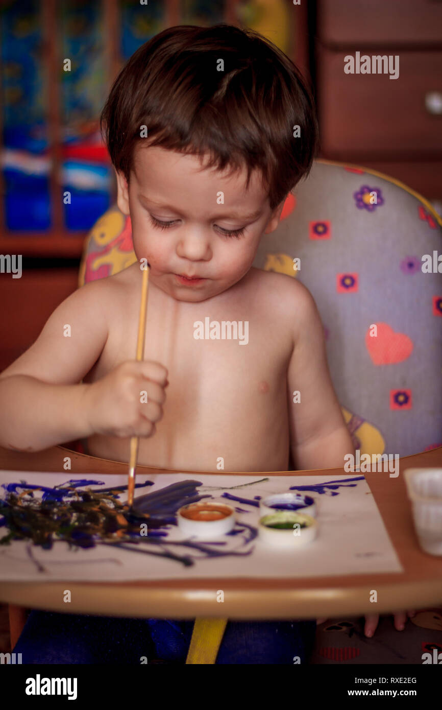 boy paints on paper. children's activities. Hobby - drawing. little boy ...