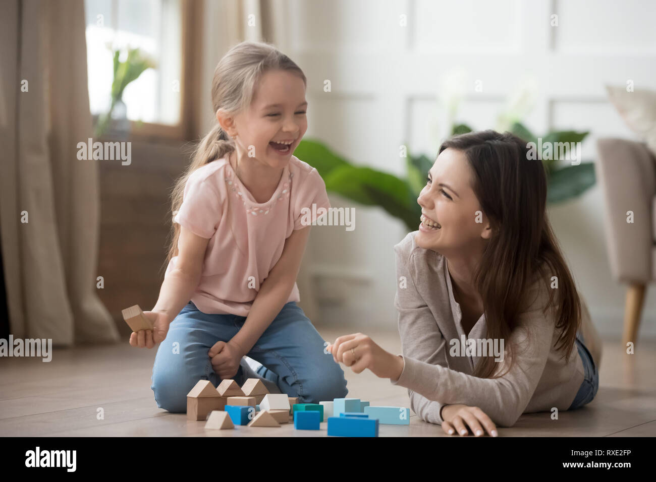 Happy mom and kid daughter laughing playing with wooden blocks Stock ...