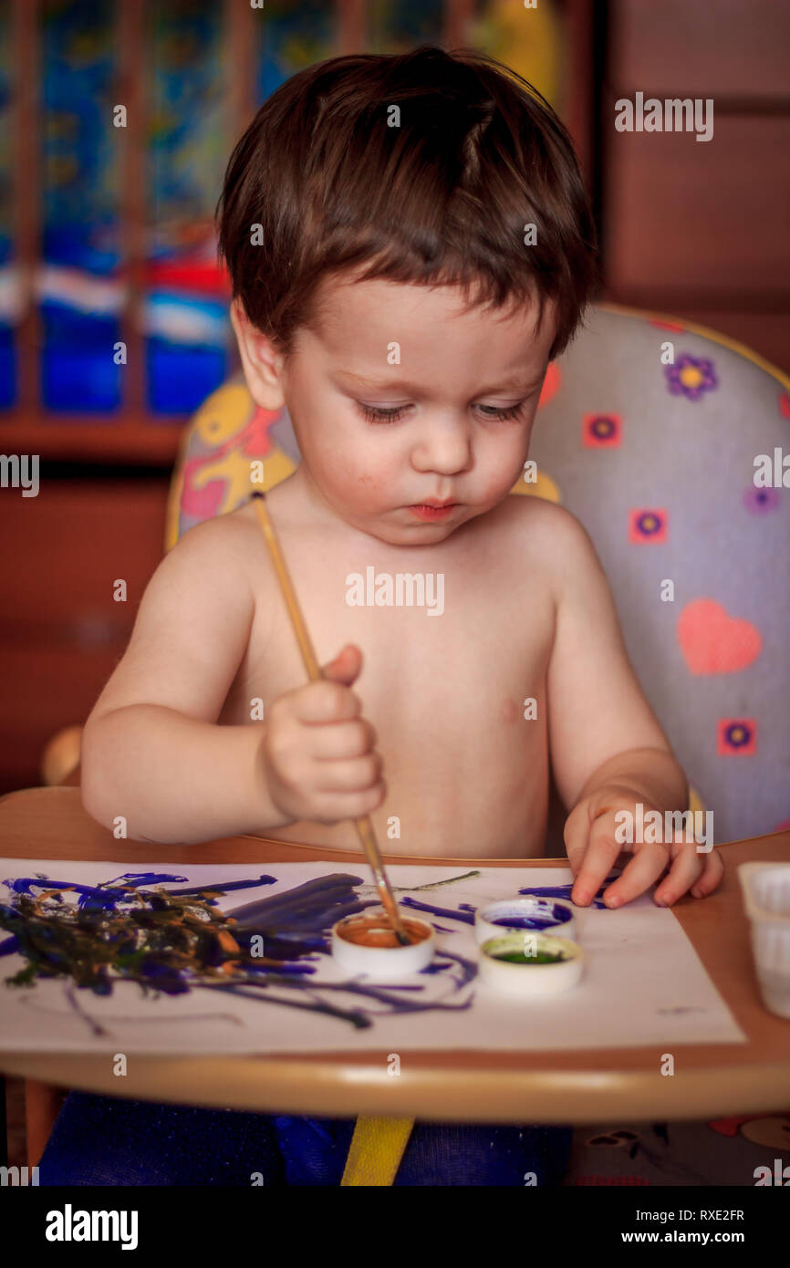 boy paints on paper. children's activities. Hobby - drawing. little boy ...