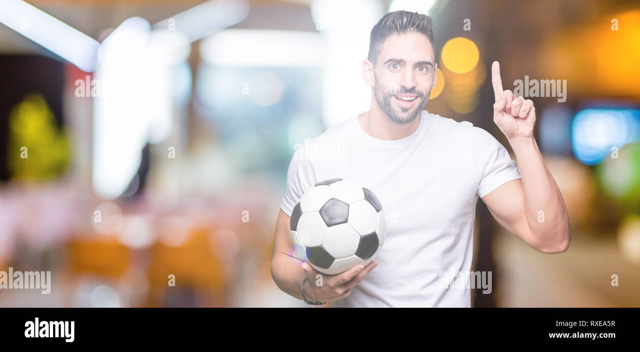 Young man holding soccer football ball over isolated background ...
