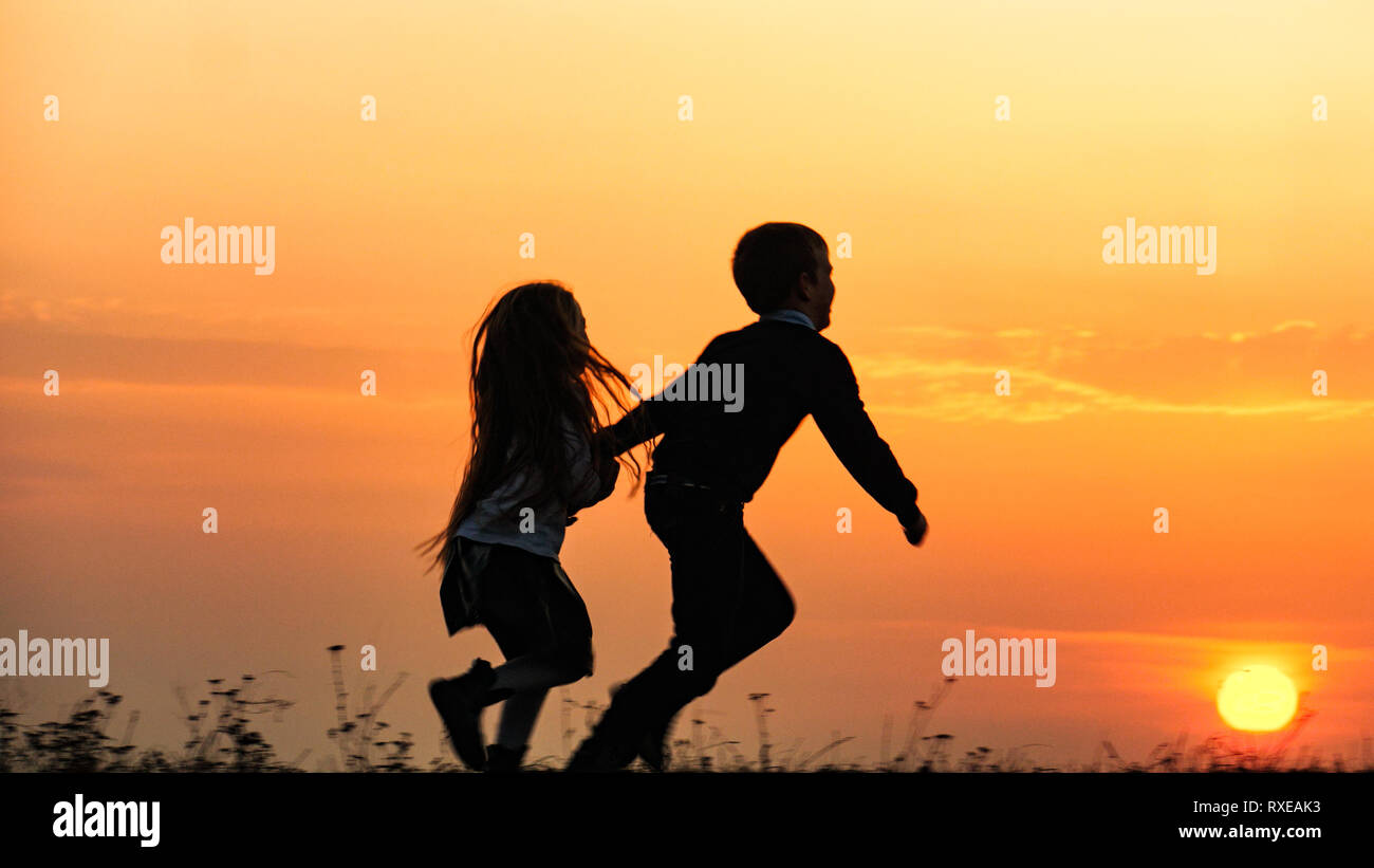 Silhouettes of two happy children during sunset Stock Photo - Alamy