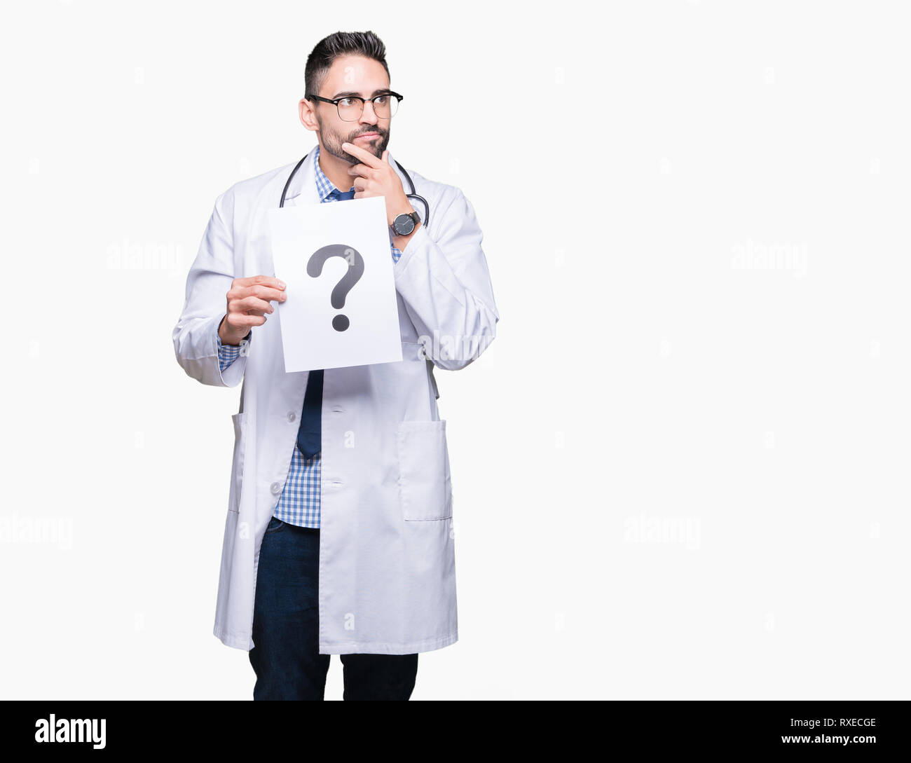 Handsome young doctor man holding paper with question mark over ...