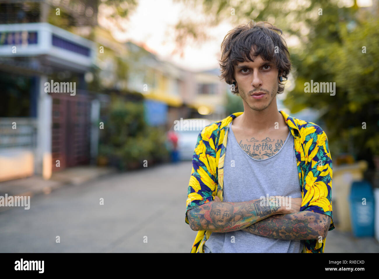 Portrait of young rebellious man with arms crossed outdoors Stock Photo ...