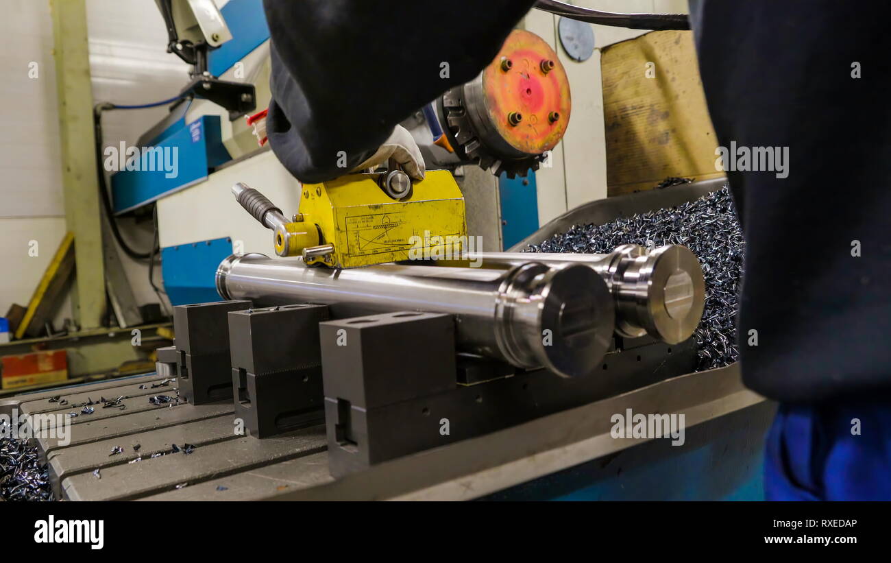 The worker placed the two metal pipes on a machine. Then unlocks the ...