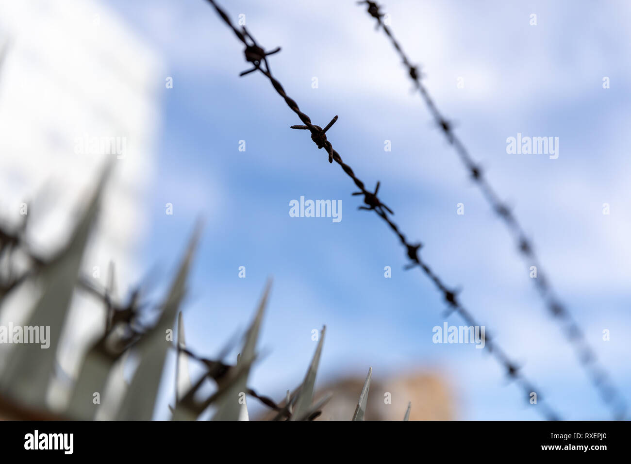 Barbed wire and spikes on a fence Stock Photo - Alamy