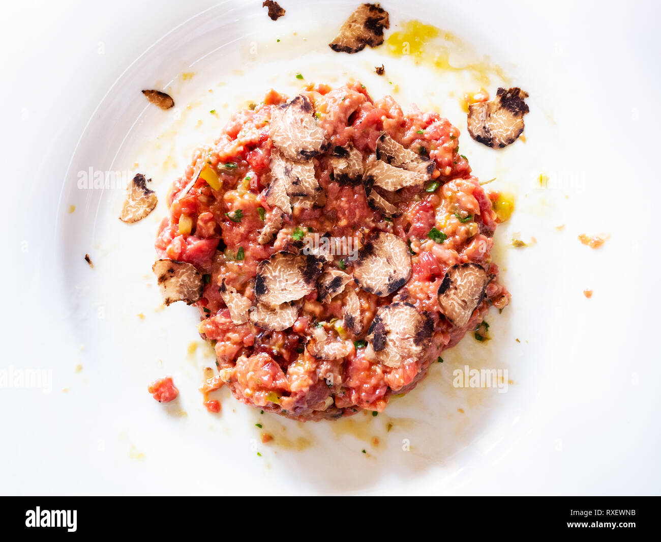 top view of beef steak tartare with raw egg and truffle on white plate ...