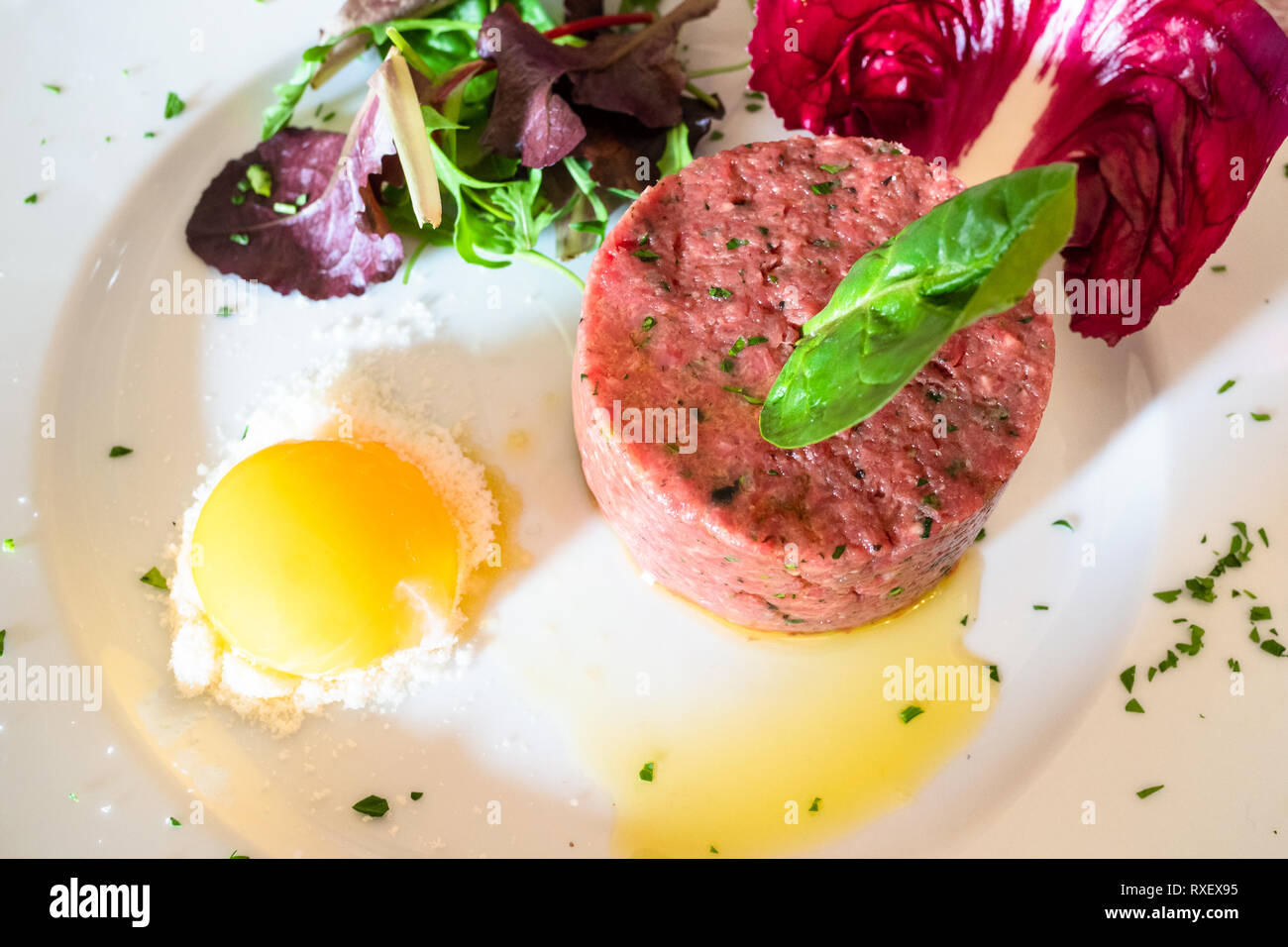 top view of tartare from ground beef with raw egg yolk on white plate ...