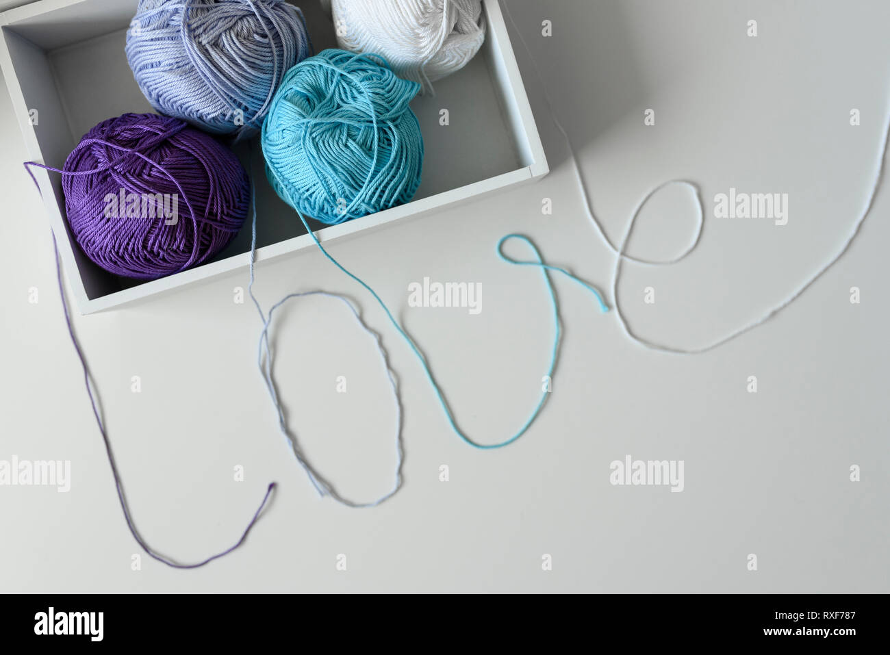 Top view of yarn balls in a wood box. Love word designed from colorful ...