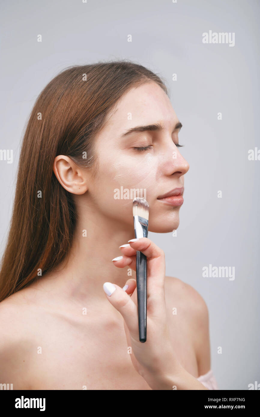 Closeup of beautiful young female model putting blush with cosmetic ...