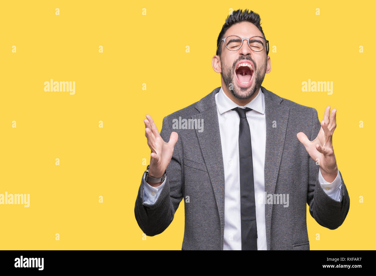 Young handsome business man over isolated background crazy and mad ...