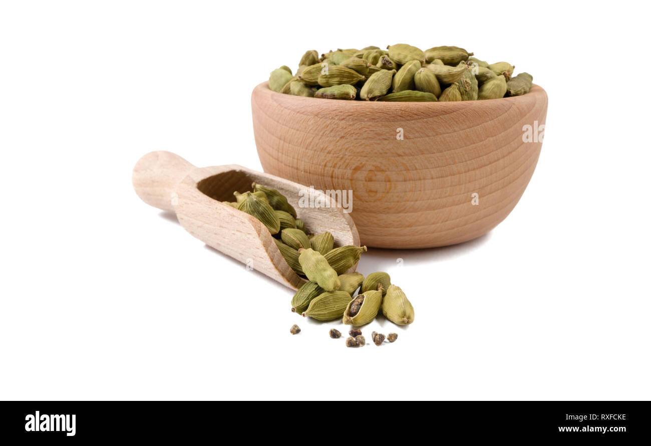 cardamon seeds in wooden bowl and scoop isolated on white background ...