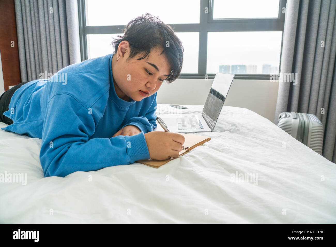 Young student writing into notes on the bed Stock Photo - Alamy