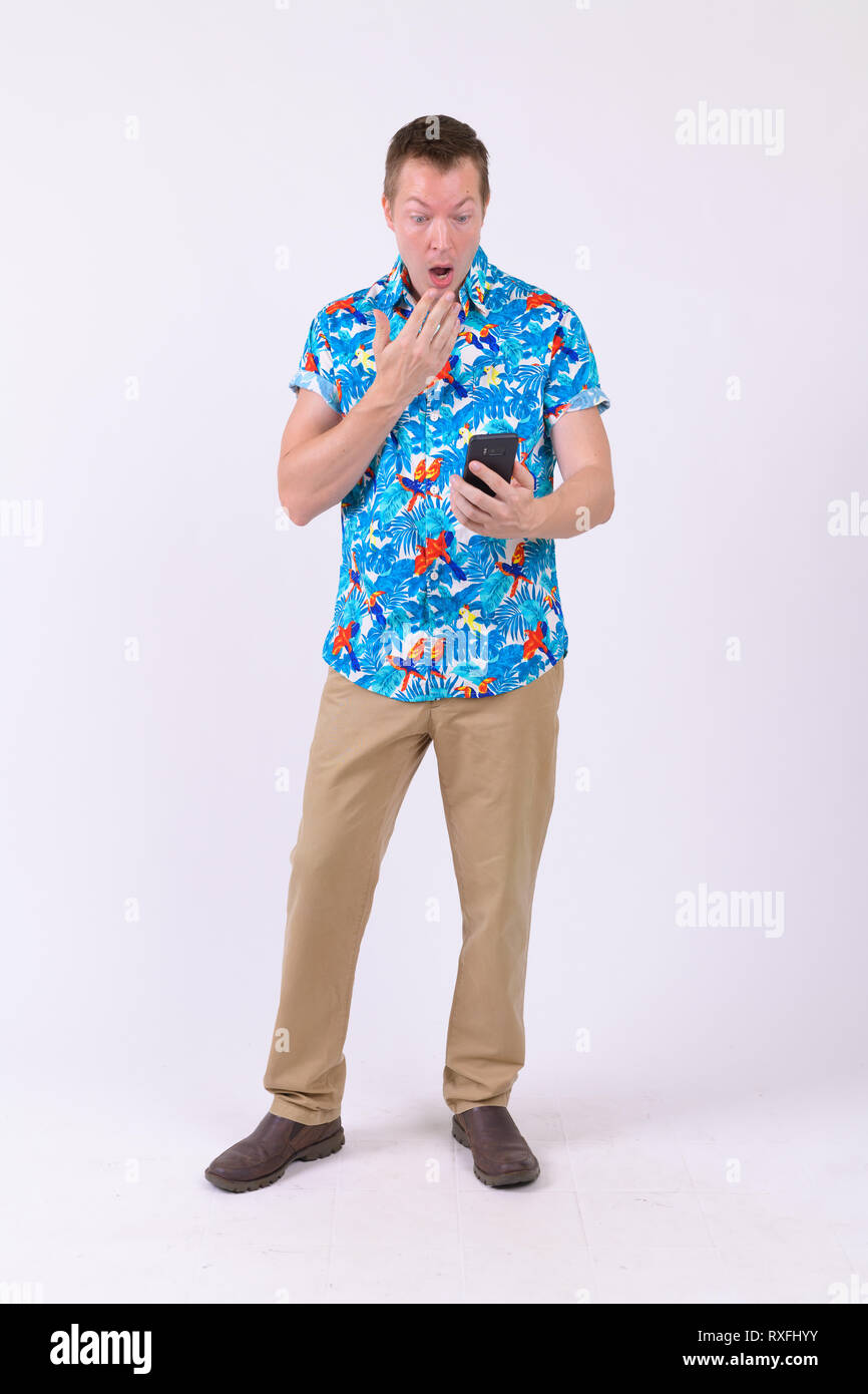 Full body shot of young tourist man looking shocked while using phone ...