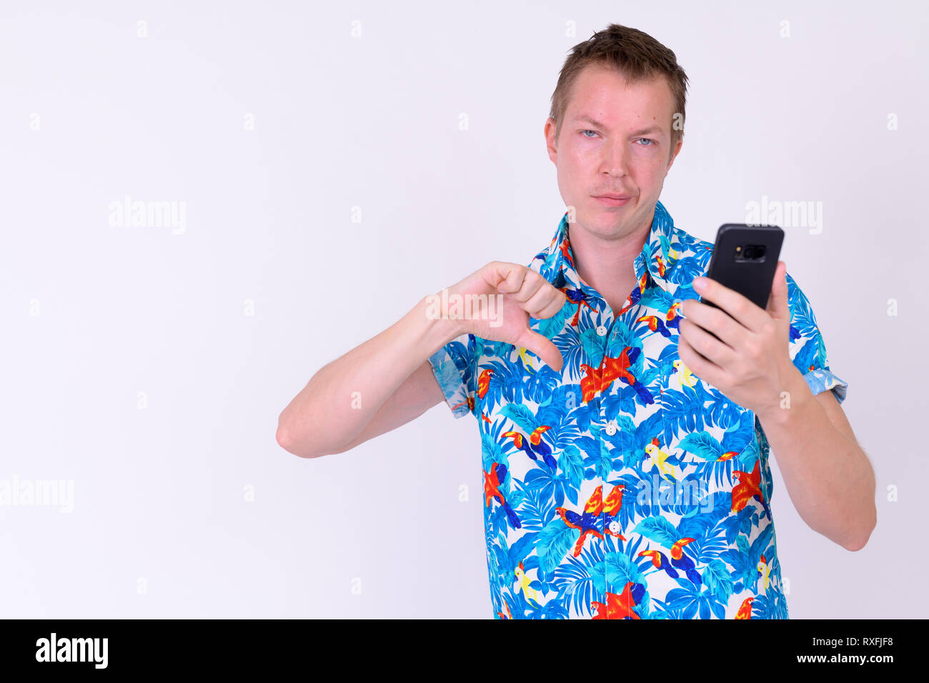 Portrait of young stressed tourist man using phone and giving thumbs ...