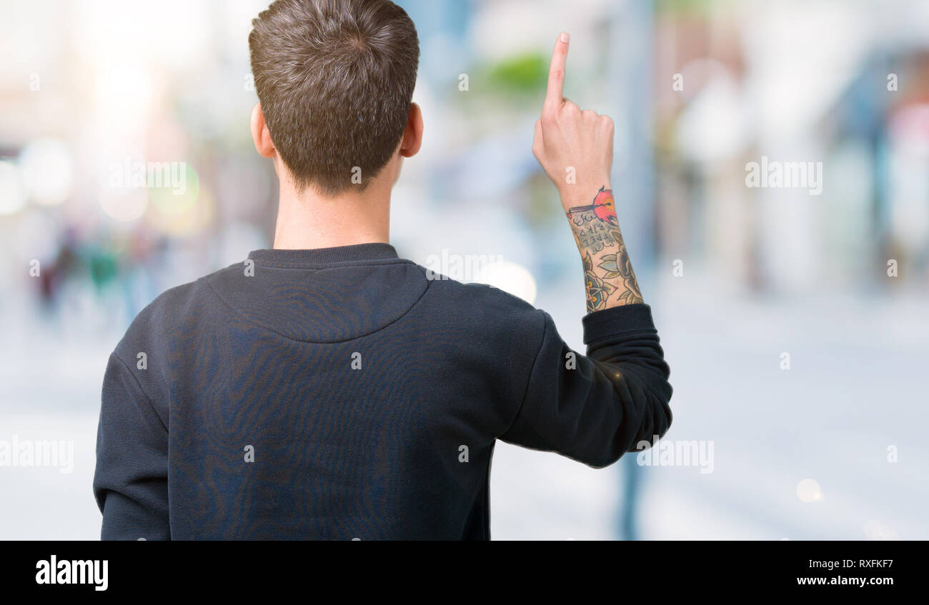 Young handsome man over isolated background Posing backwards pointing ...
