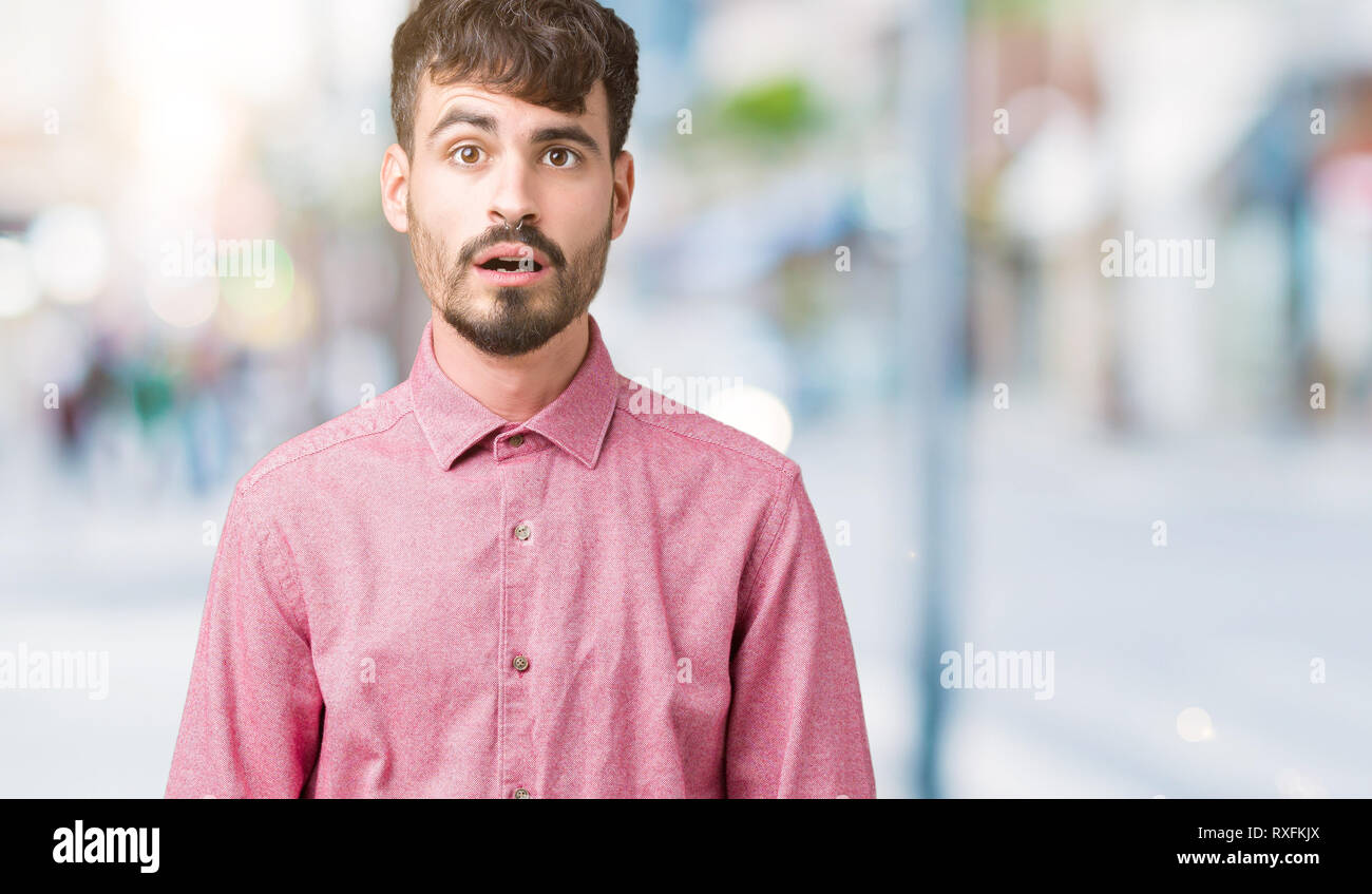 Young handsome man wearing pink shirt over isolated background afraid and shocked with surprise ...