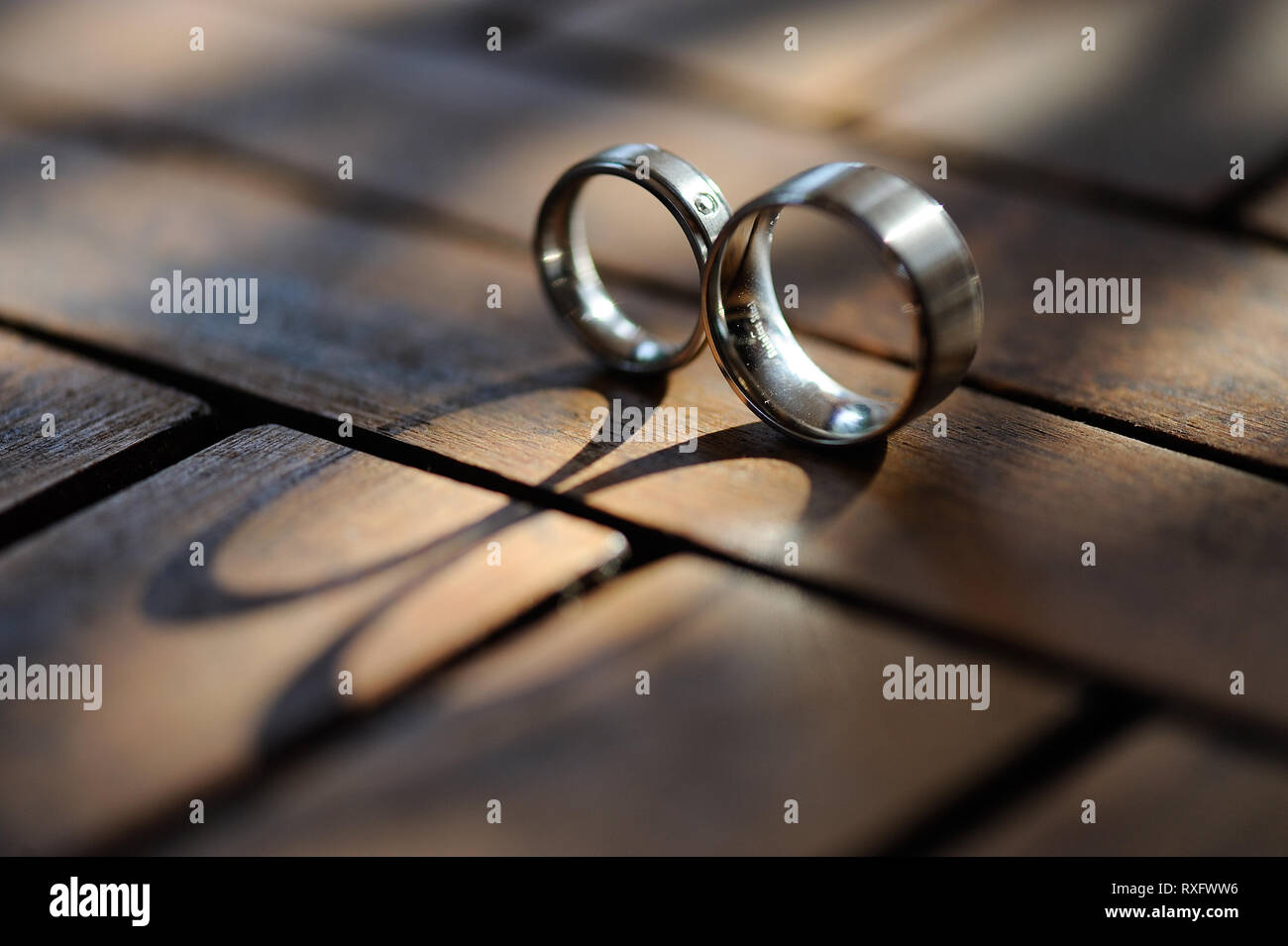 two steel rings on wooden table casting elongated shadows, with the ...
