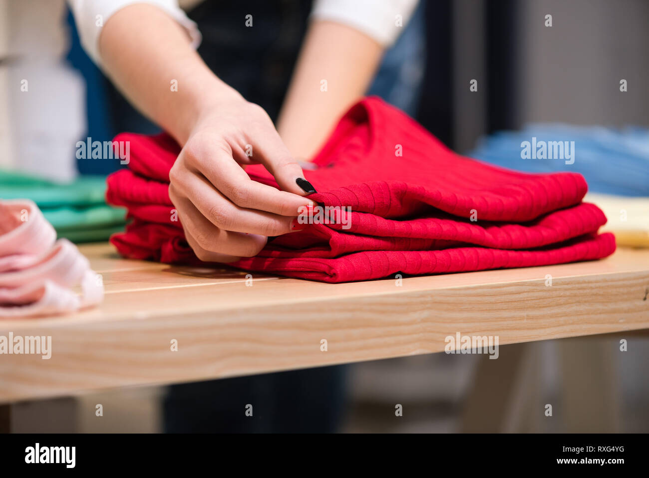 Female hands fold red shirts at clothing store Stock Photo - Alamy