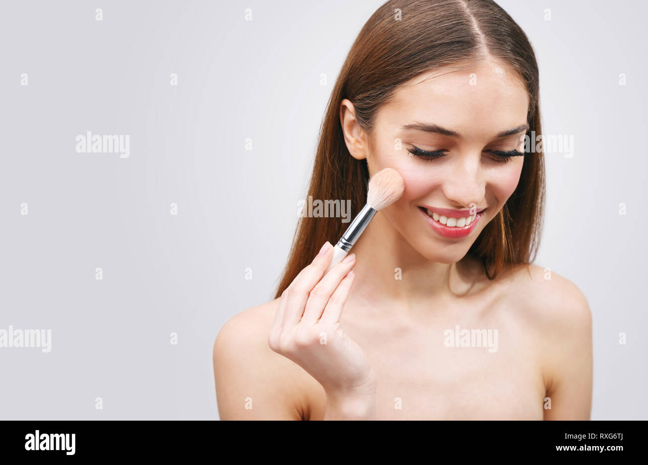 A young woman applied liquid foundation on her face with a brush Stock ...