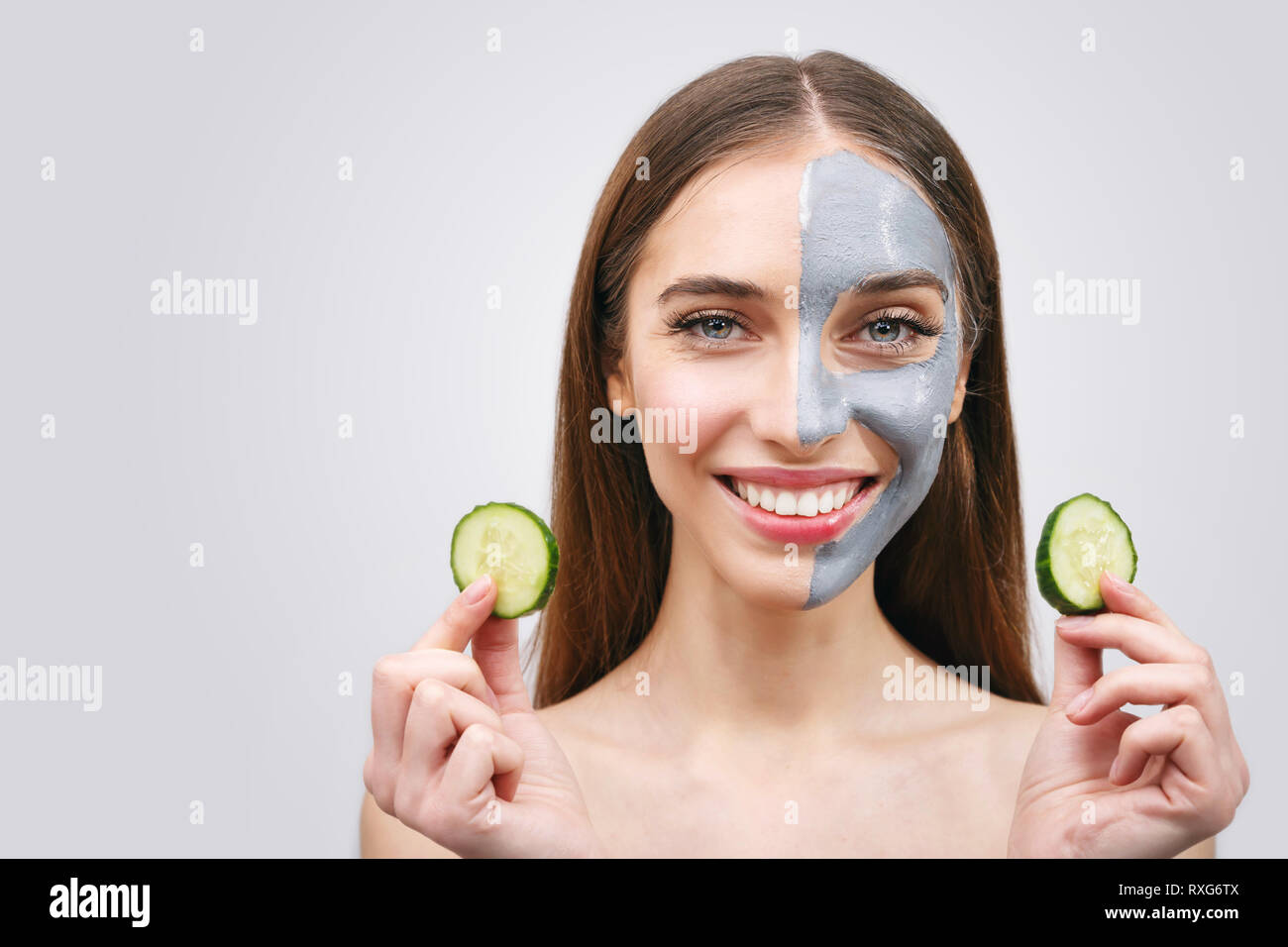 Young woman with clay facial mask holding cucumber slices isolated on white background Stock ...