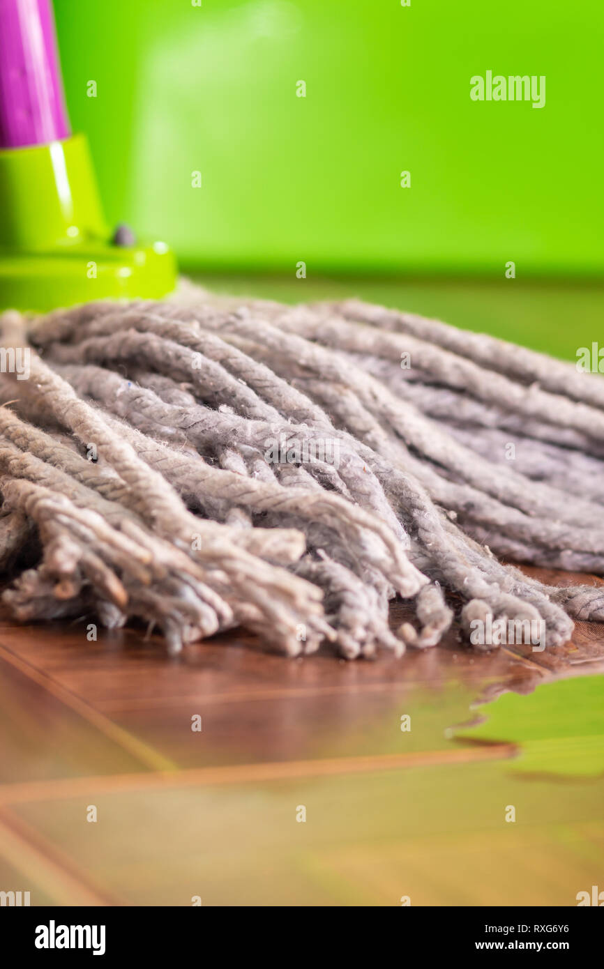 Rope mop on the tile floor and a puddle of water. Home cleaning and ...