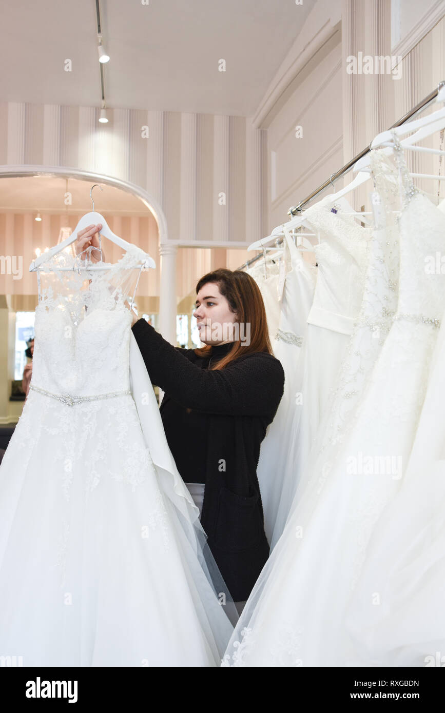 2 shop assistants are helping a pretty red haired girl in a Wedding ...